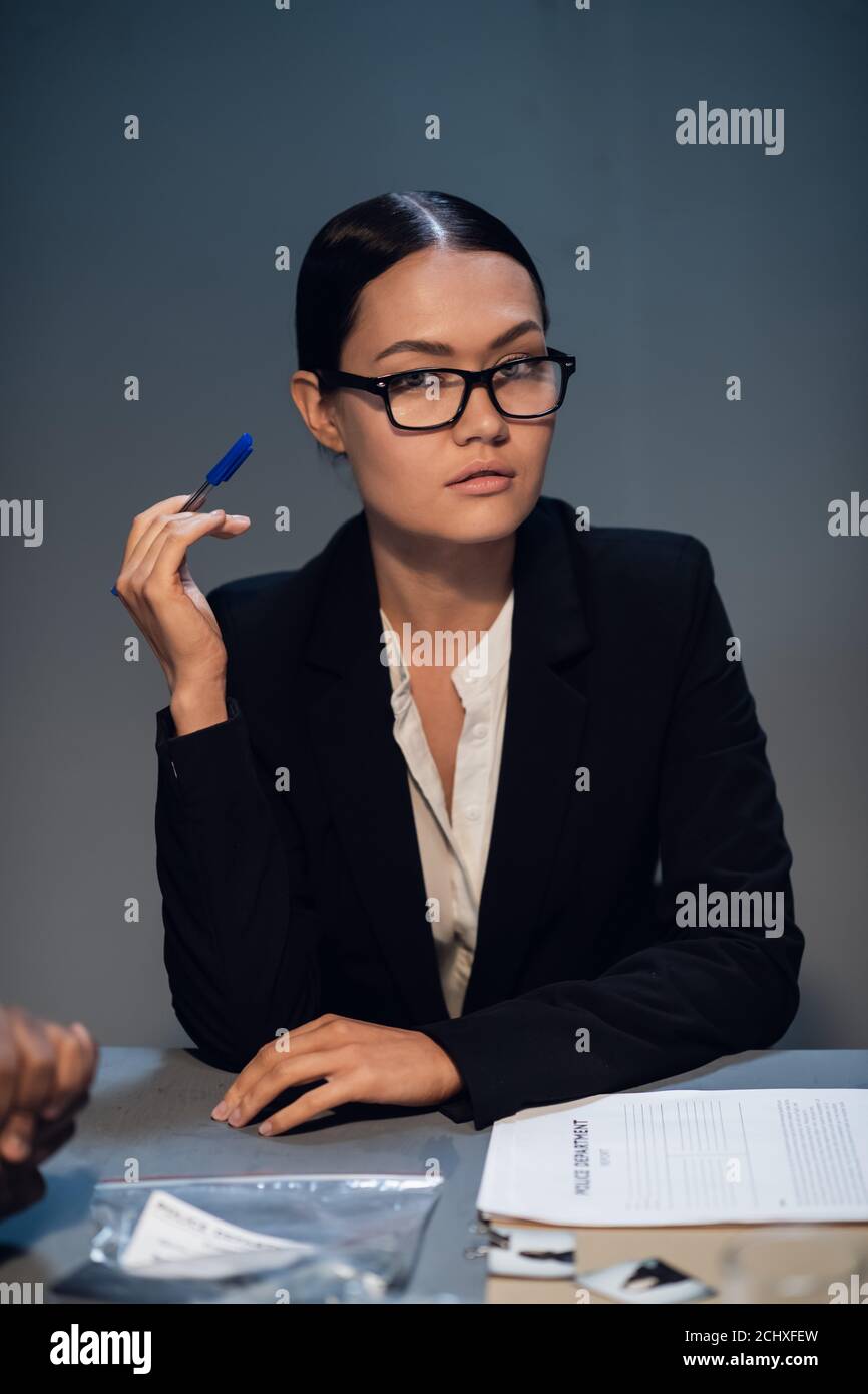The state prosecutor in a black business suit and glasses sits at a ...