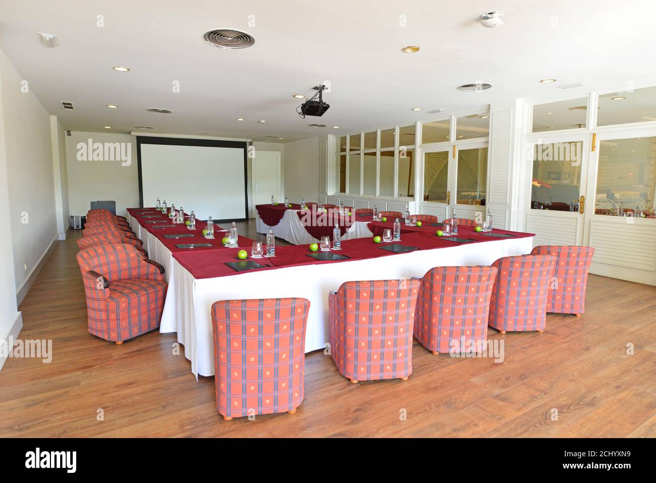 Inside of a conference hall with set-up chairs and tables and a screen ...