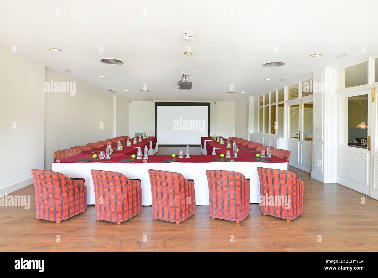 Inside of a conference hall with set-up chairs and tables and a screen ...