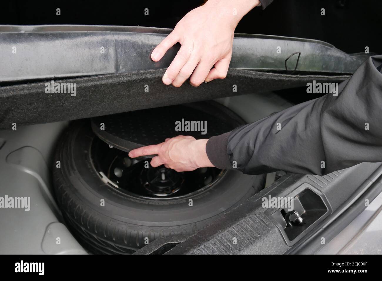 Spare wheel in the trunk. Auto mechanic hands Stock Photo - Alamy