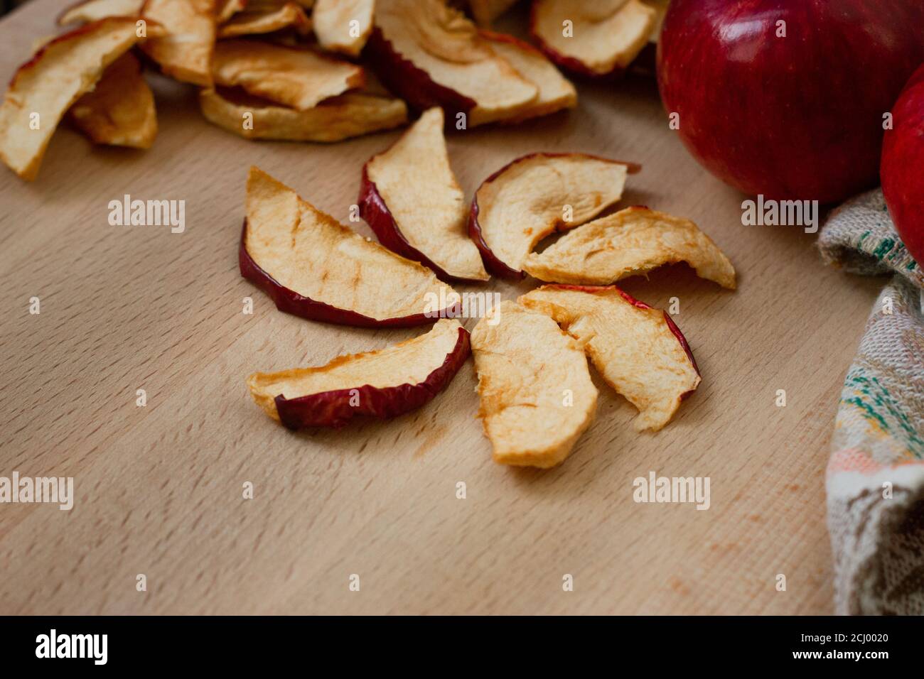 Dried slices of apple and red apples on the wooden board. Selective ...