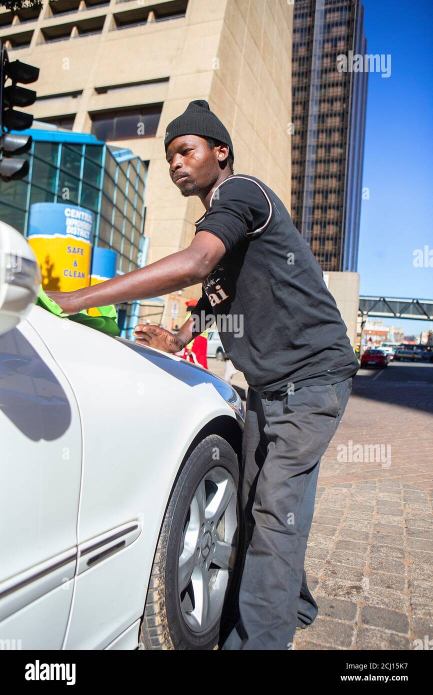 African young male washing a car in city centre of Johannesburg, South ...