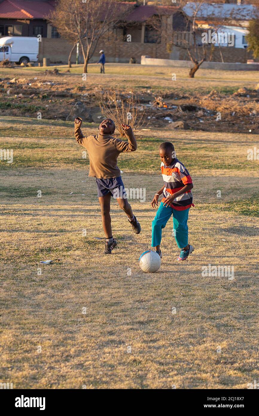 African boys playing a game of soccer (football) in a park in Soweto ...