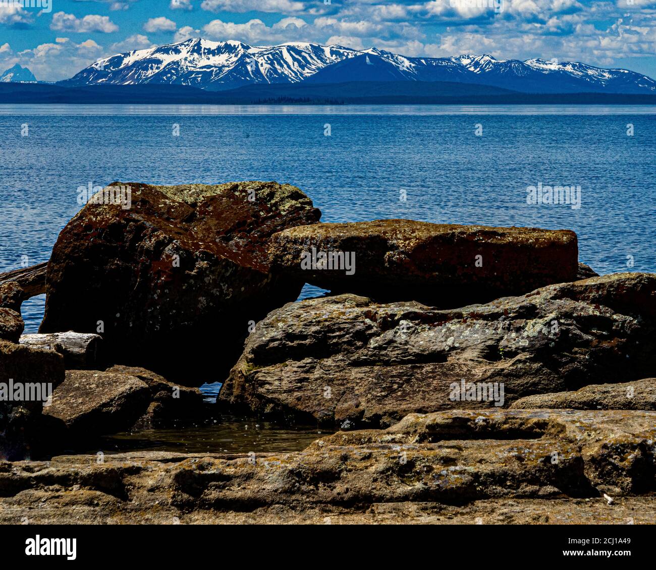 rocks at end of abandoned pier in yellowstone lake, mountains in the ...