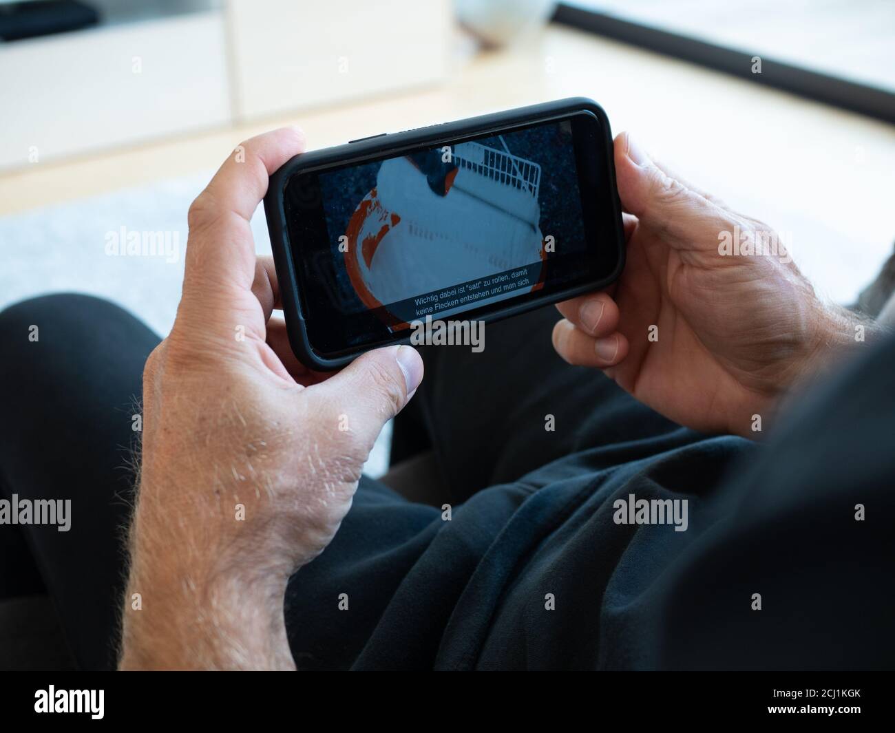 Man watching a YouTube video on phone (iPhone) with craftsman painting ...