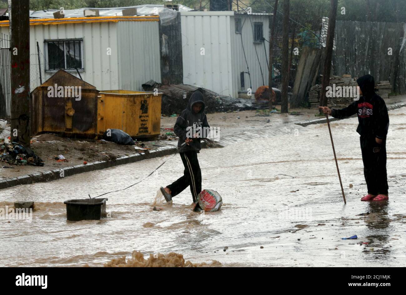 A Palestinian boy walks though a flooded road on a rainy day in Beit ...