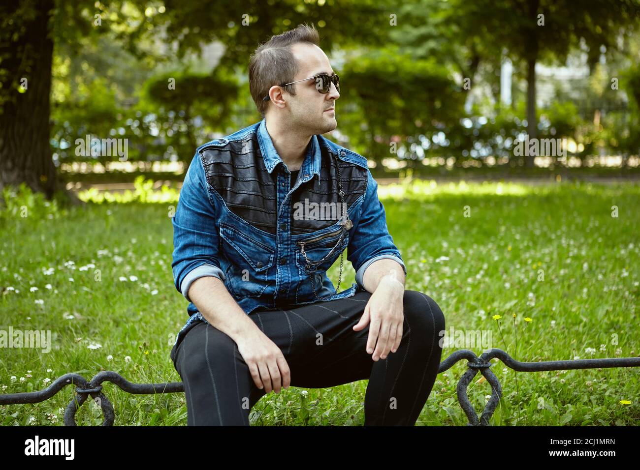 Russian man 27 years old is sitting on the lawn fence in the public ...