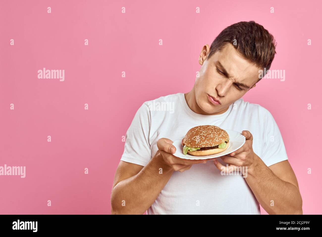 Emotional guy with hamburger on a plate and white t-shirt pink ...