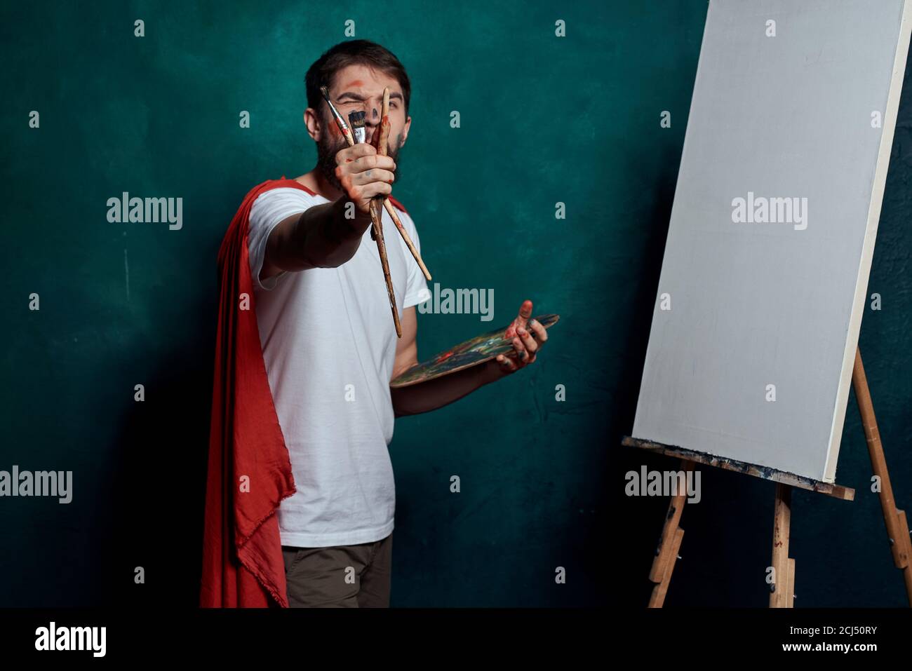Male artist red cloak drawing easel art green background image Stock ...