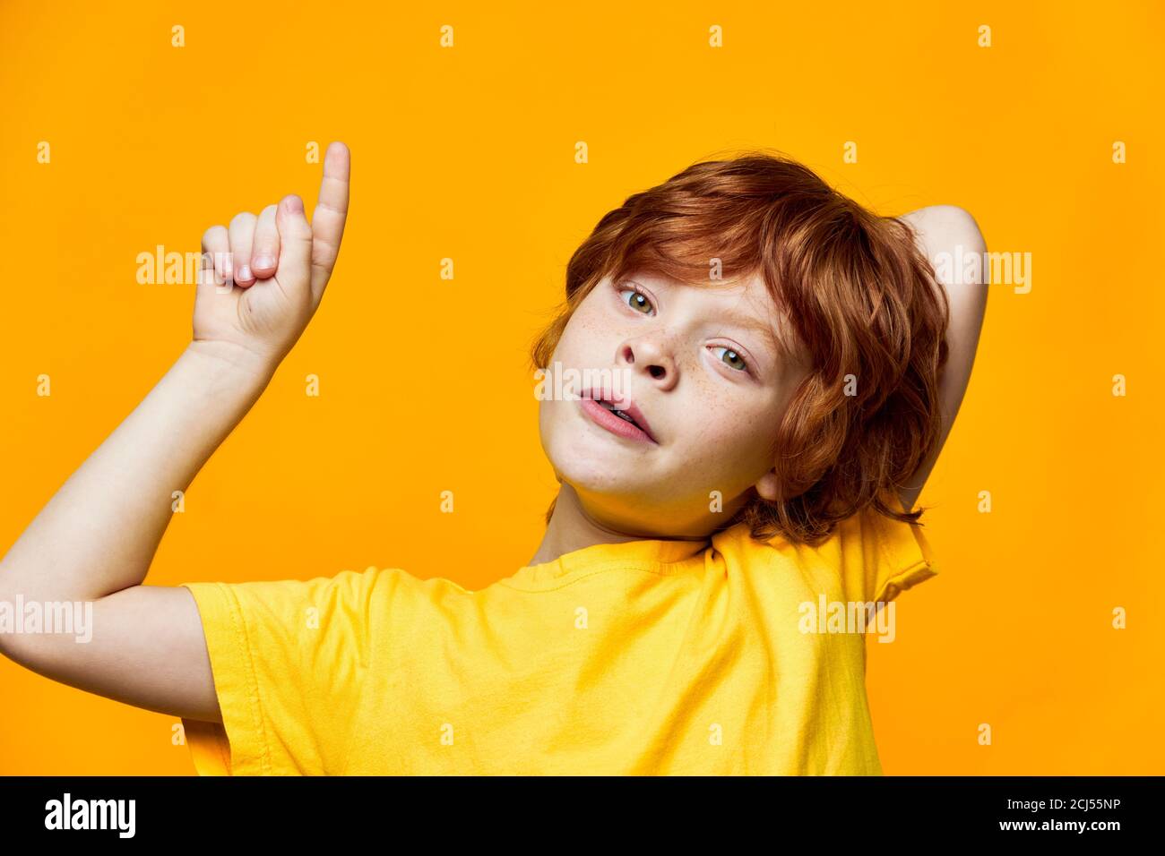 Portrait of a cute little boy with ginger-haired gestures with his ...