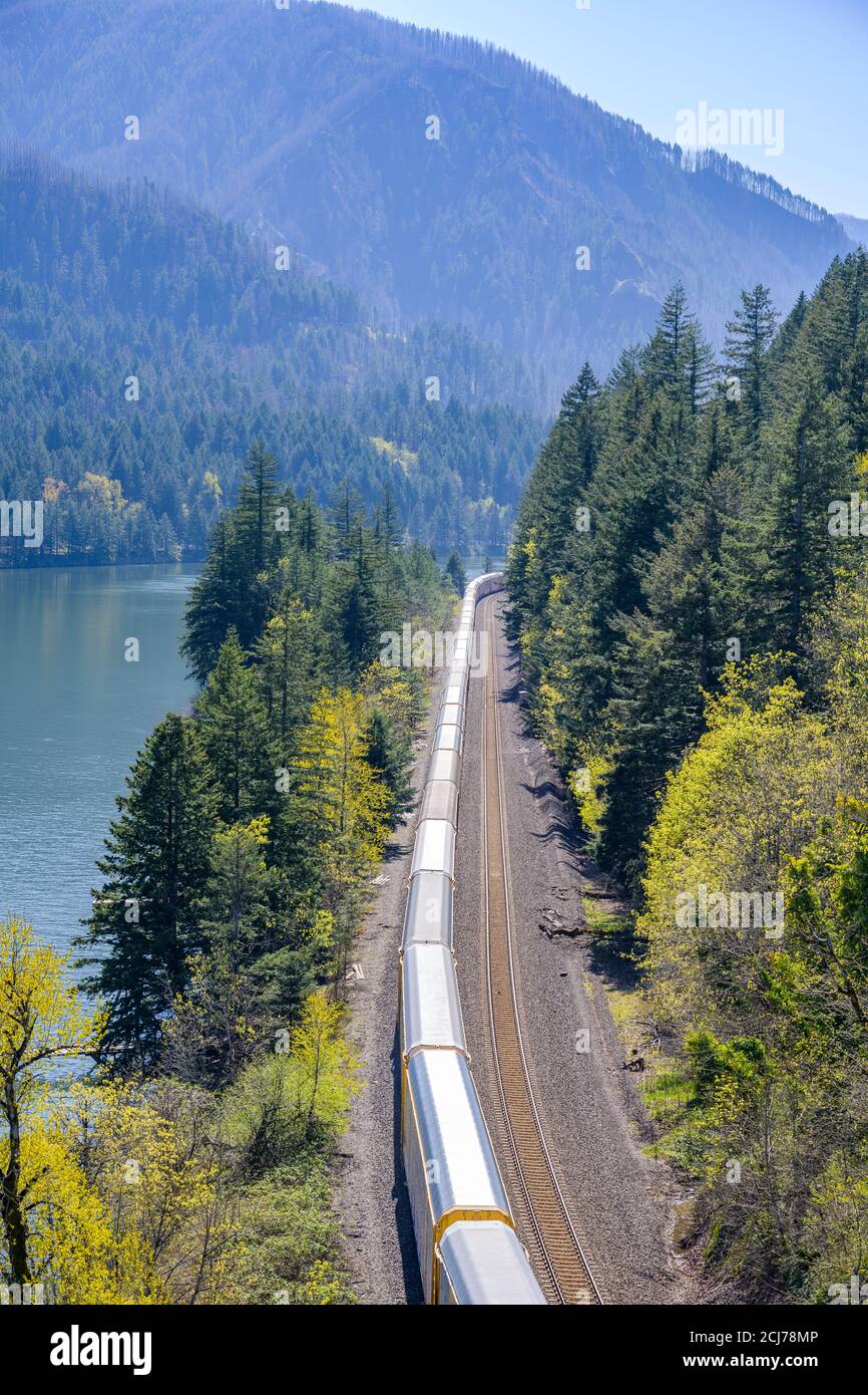 Landscape with a freight train on a railroad running along the banks of ...