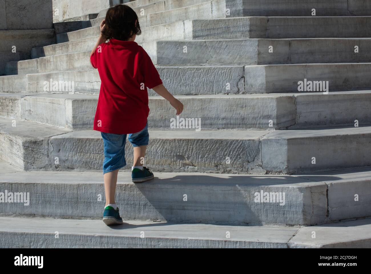 Closeup focus shot from behind of a young boy climbing up the stairs ...
