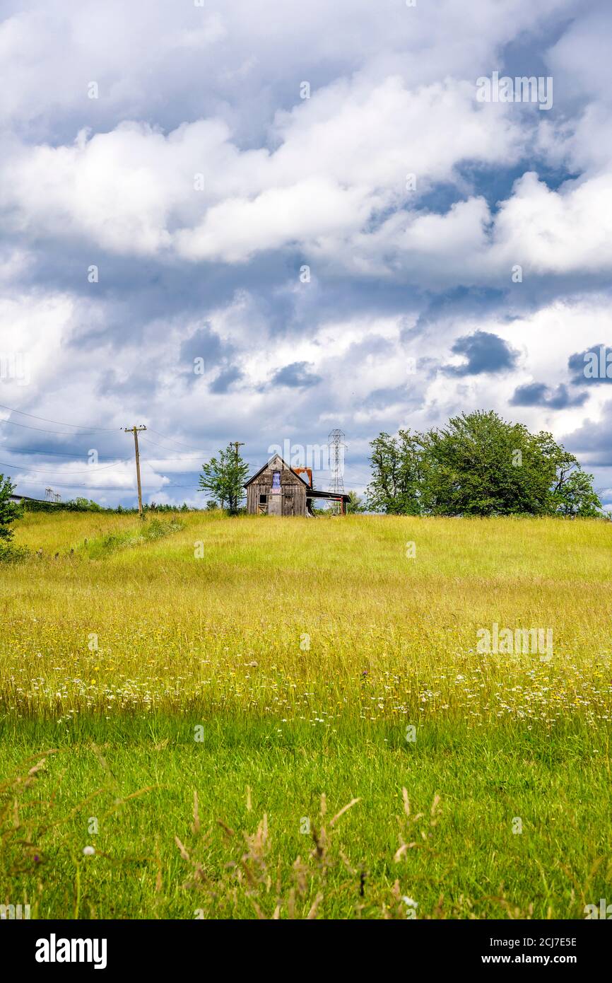 Rural summer landscape with old rickety wooden hay barn standing under ...