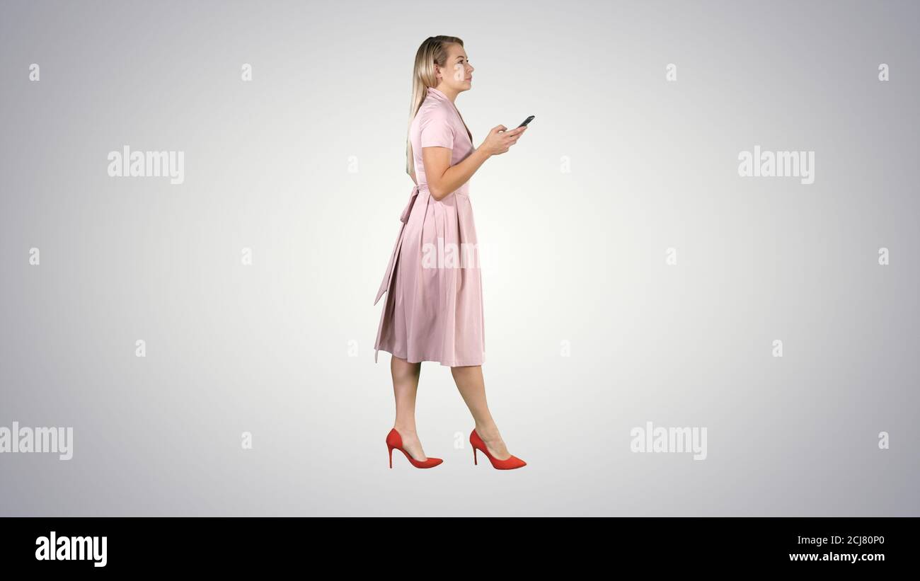 Pretty blonde woman using cell phone texting message on gradient Stock ...