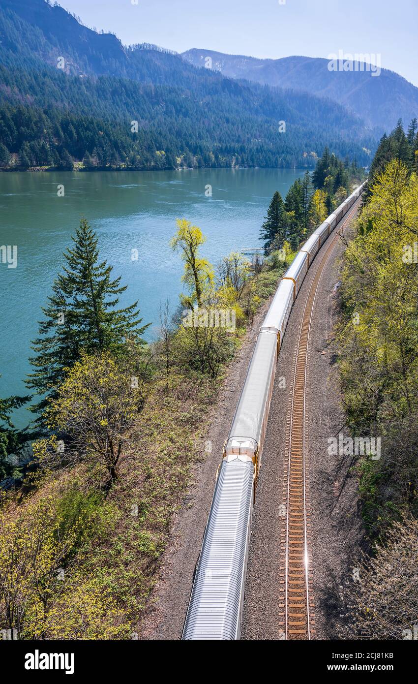 Landscape with a freight train on a railroad running along the banks of ...