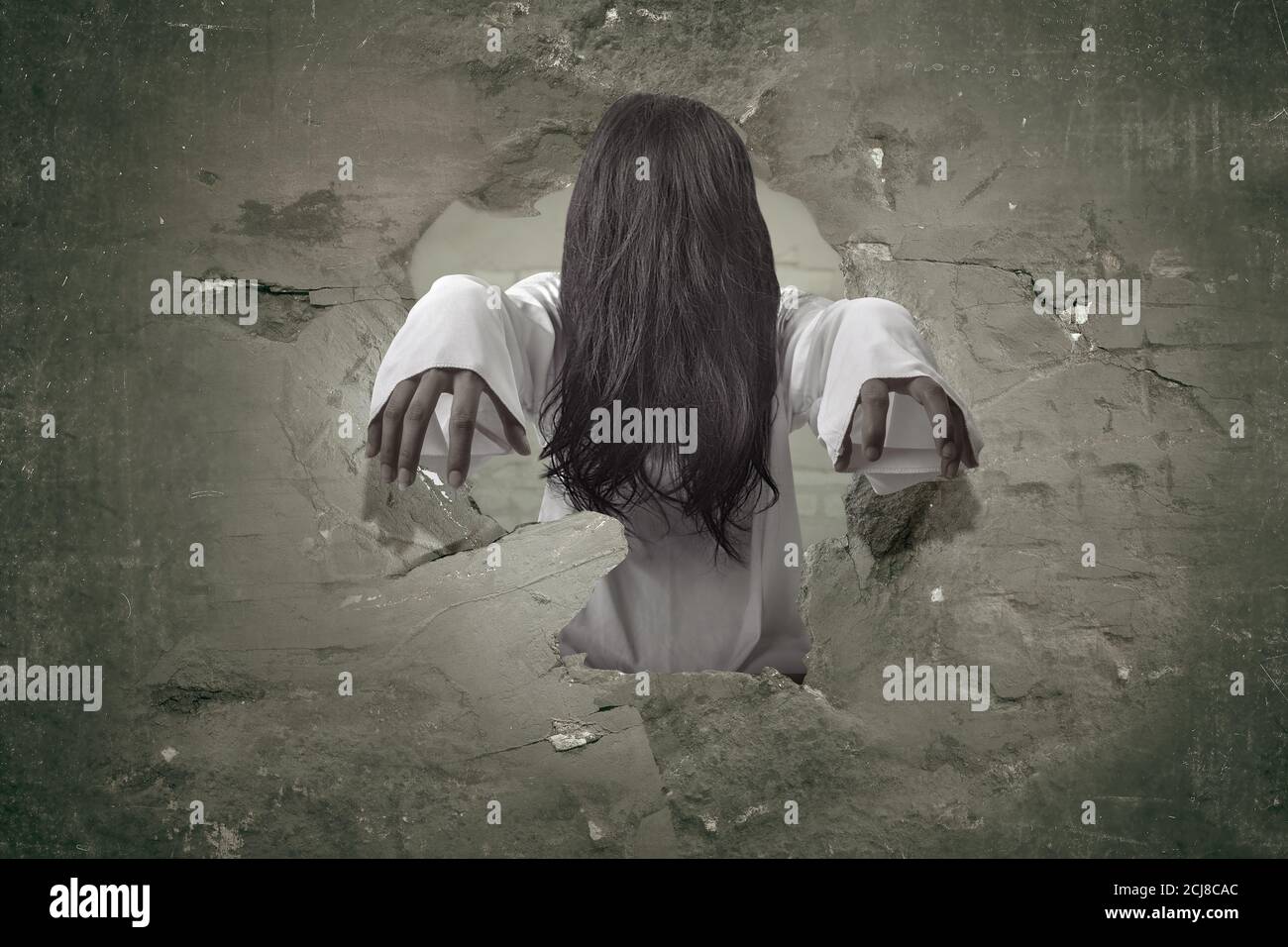 Scary ghost woman coming out from a hole in the wall. Halloween concept ...