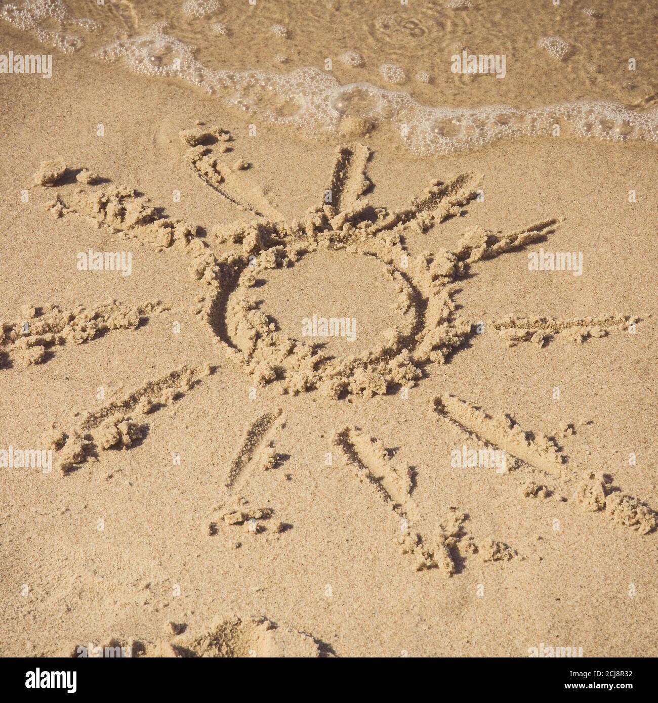 Shape of sun on sand at beach and incoming sea wave. Concept of summer ...