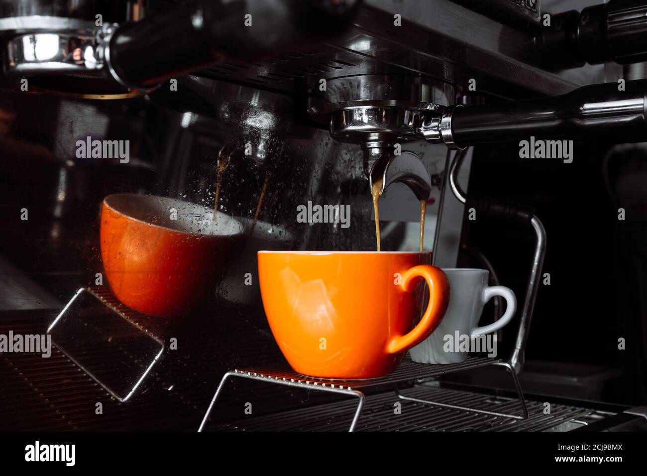 Coffee is poured into two cups from a coffee machine. Coffee ...