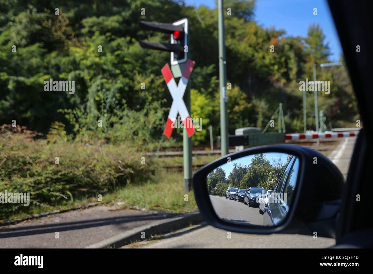 Line of cars seen in the side mirror of a car at the railway crossing ...