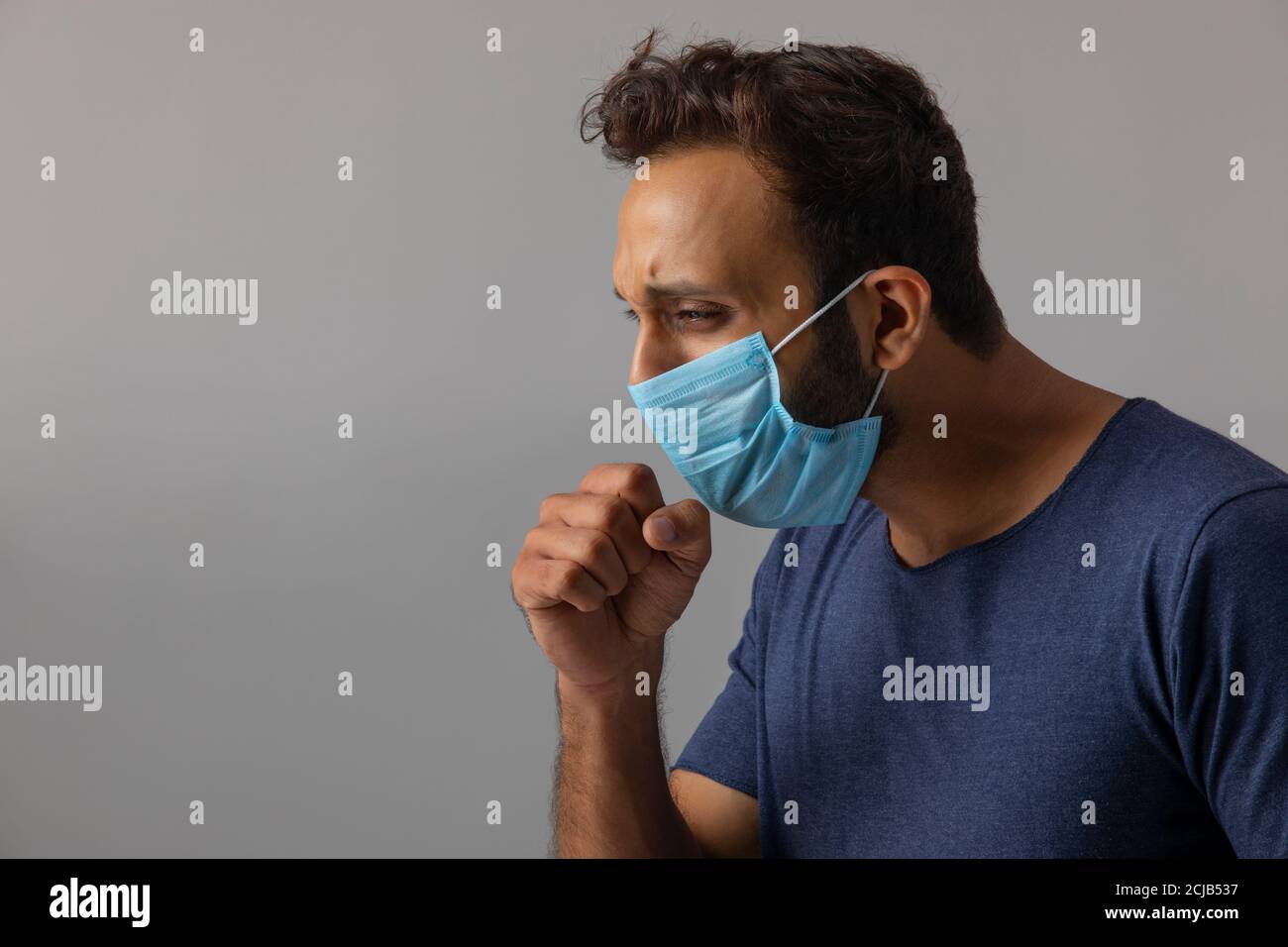 Young man coughing with his mask on Stock Photo - Alamy