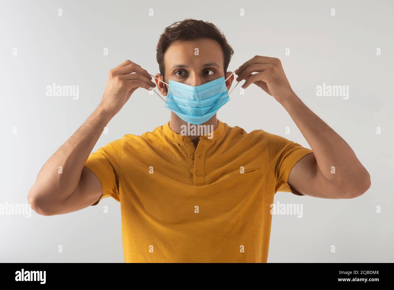 Portrait of a young man taking precautions by covering his face with a ...