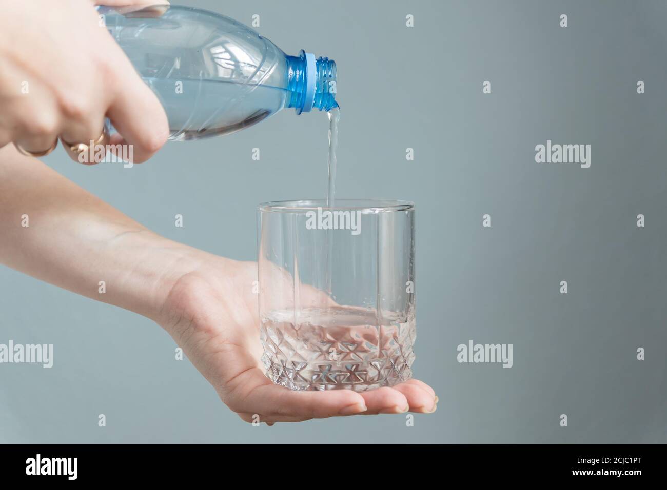 woman pouring water into a glass on gray background Stock Photo - Alamy