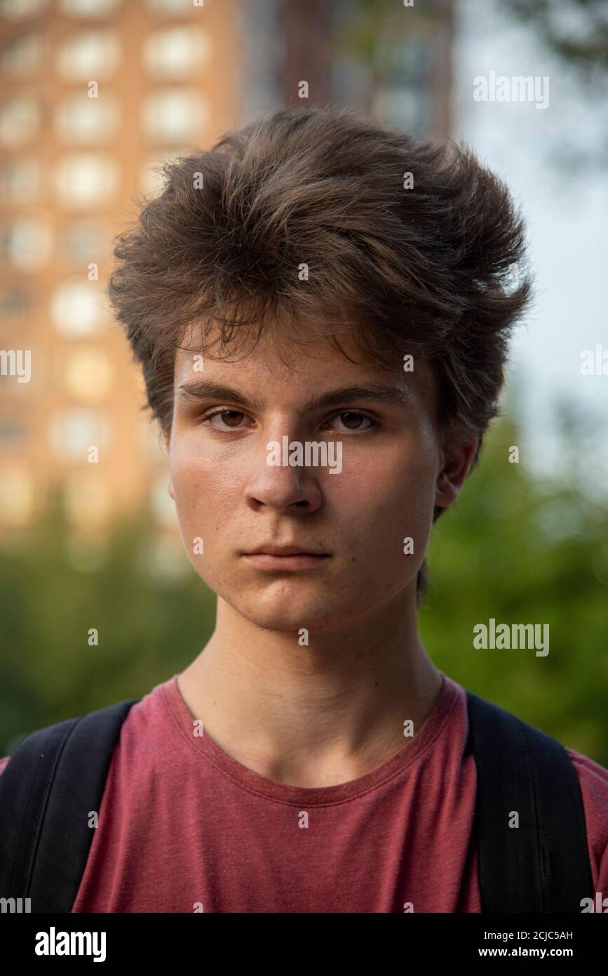 Portrait of a young teenager 17 years old in a red t-shirt with thick ...