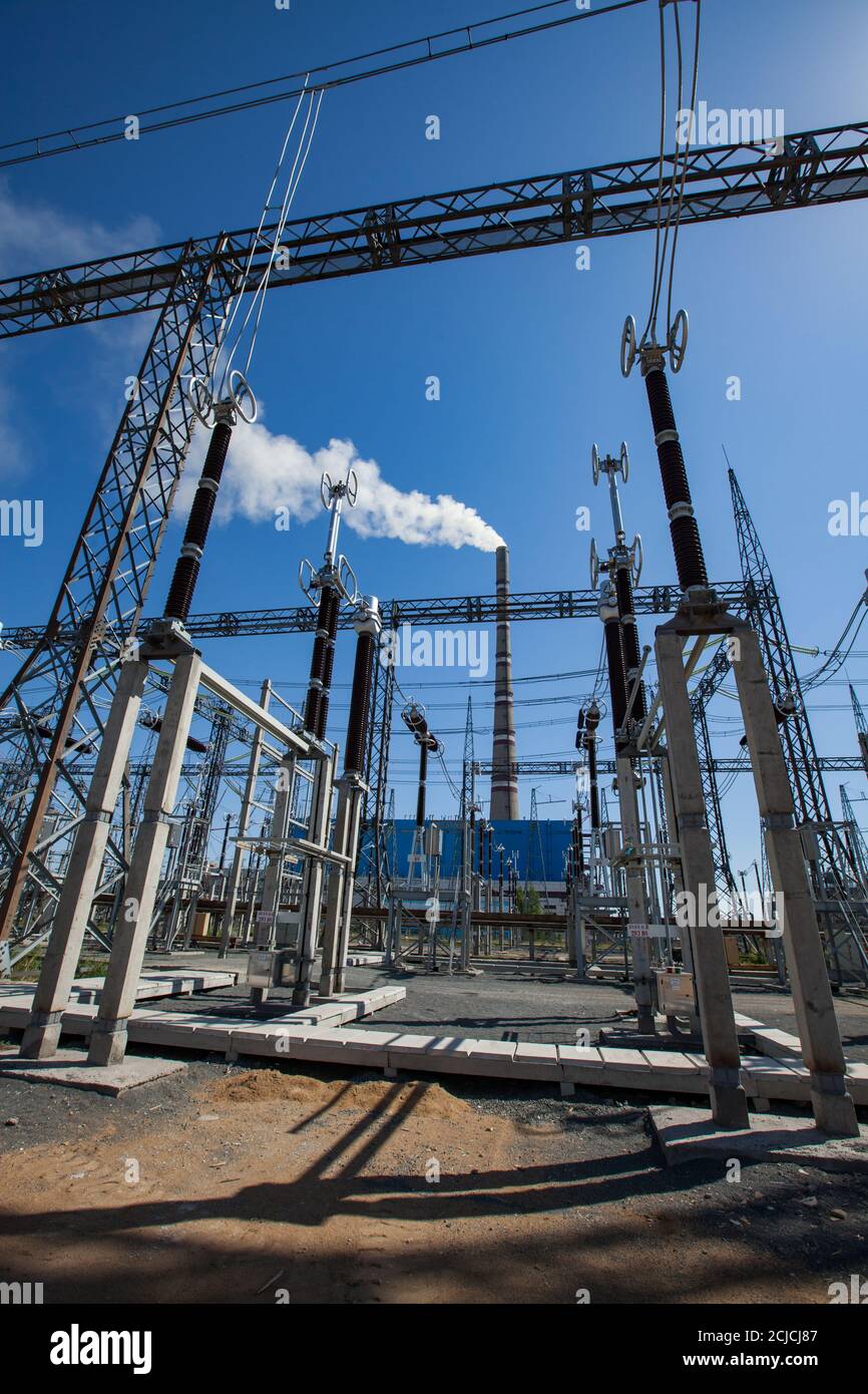 Electrical substation. Electric pylon grids on blue sky and smoking ...