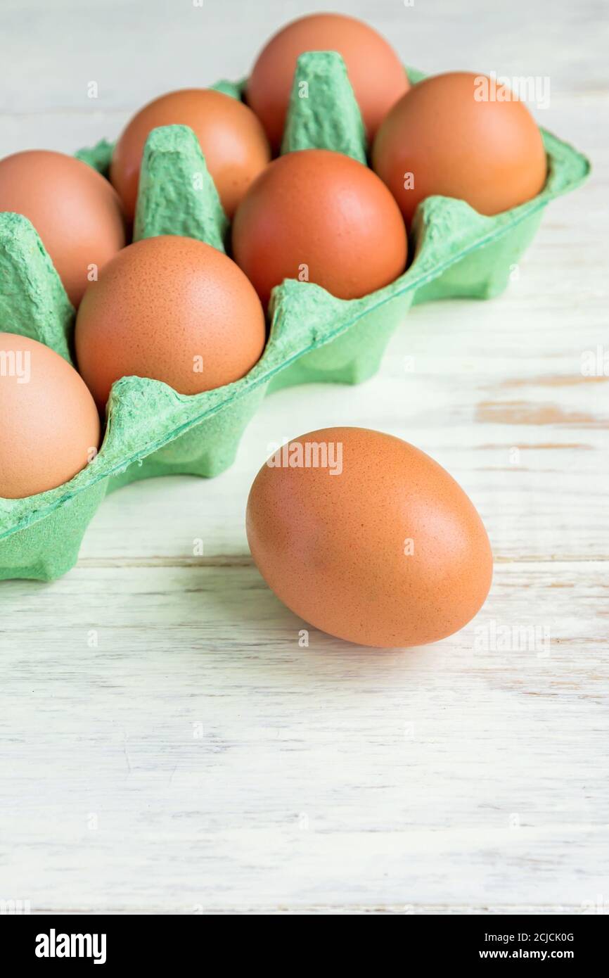 close up of raw brown chicken eggs in egg carton box on wooden table ...