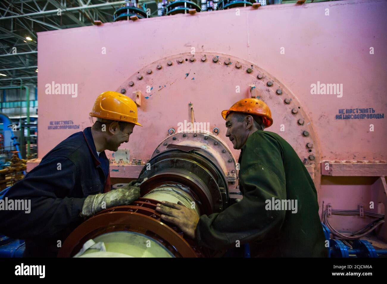 Electric power station. Two workers fixing pink electric machine ...