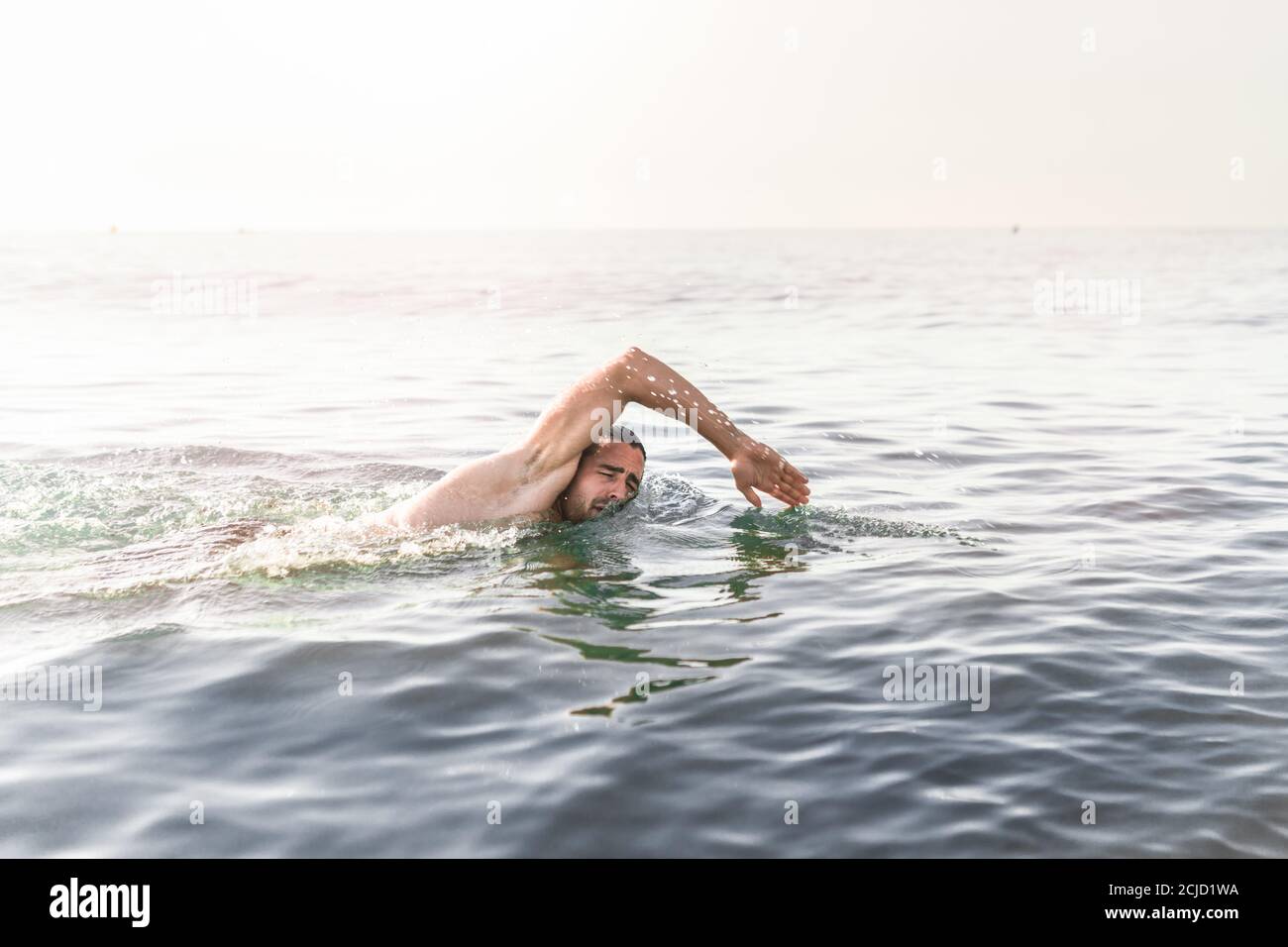 Young athletic Caucasian male swimming in the sea in the early morning ...