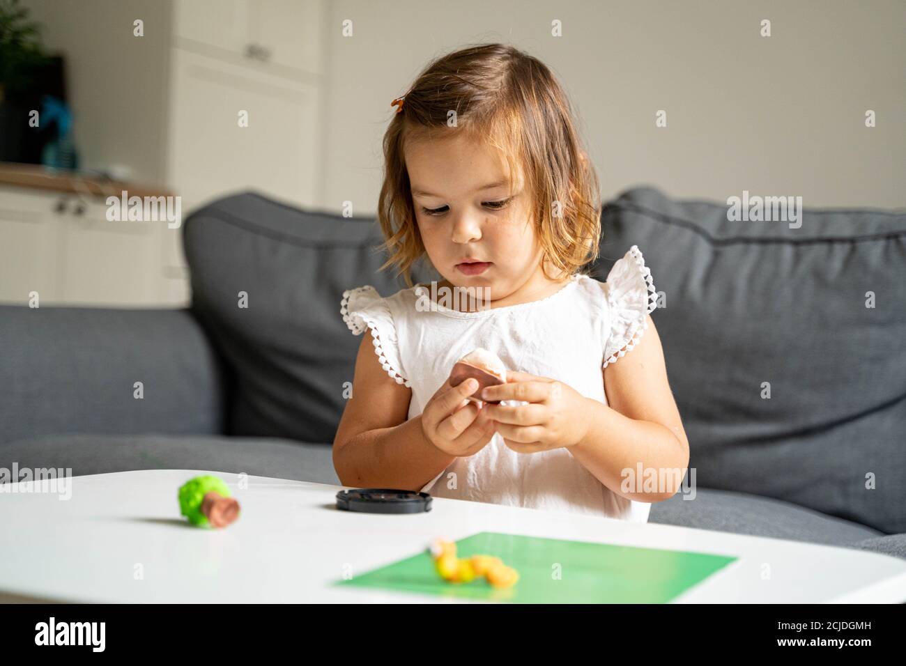 Caucasian toddler girl playing modeling play dough at home with mother ...
