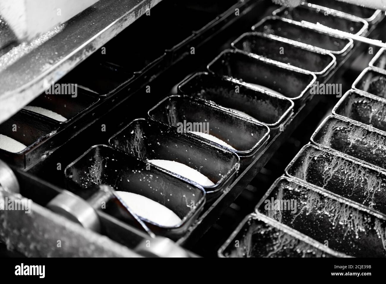 Industrial bakery automated line. Filling metal molds for baking bread ...