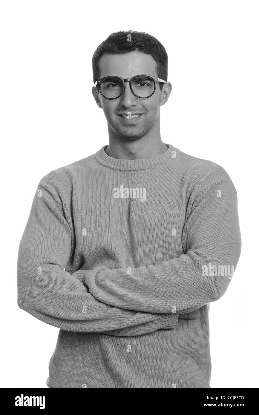 Portrait of happy young handsome Persian man smiling with arms crossed ...