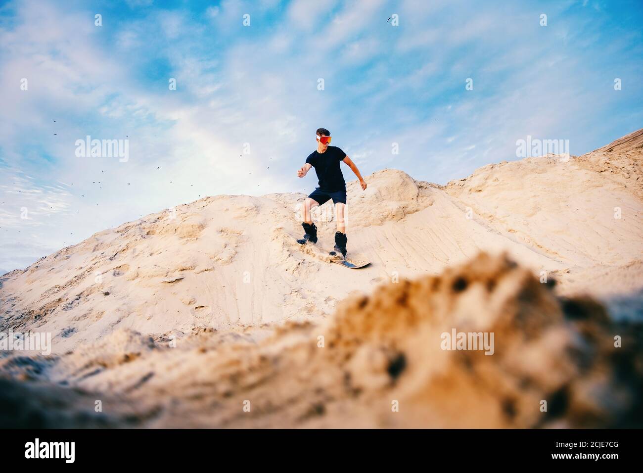 Extreme descent sand on snowboard in desert. Male snowboarder on dunes ...