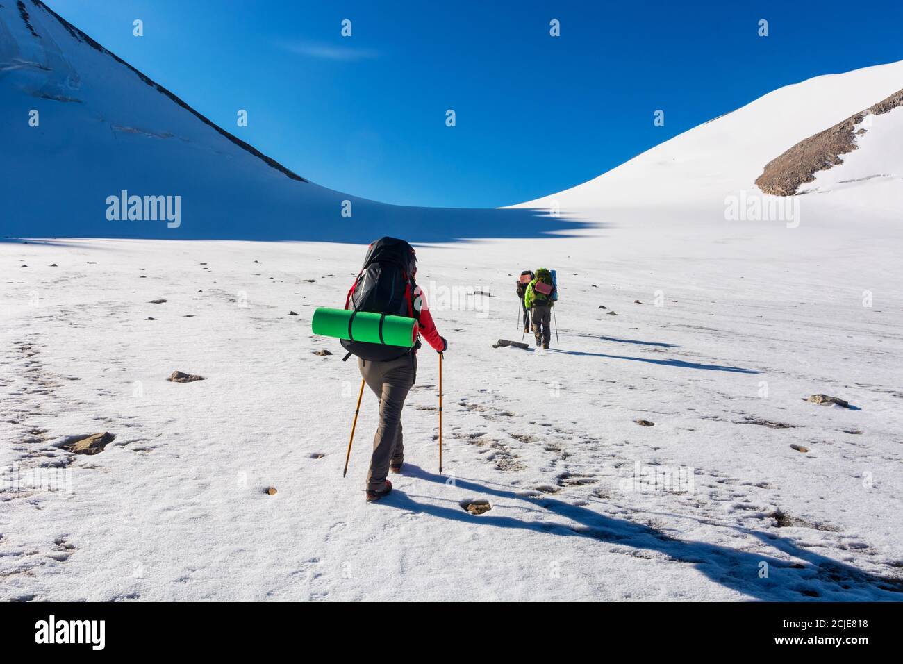 Group of tourists with backpacks lift up mountain trail to glacier in ...