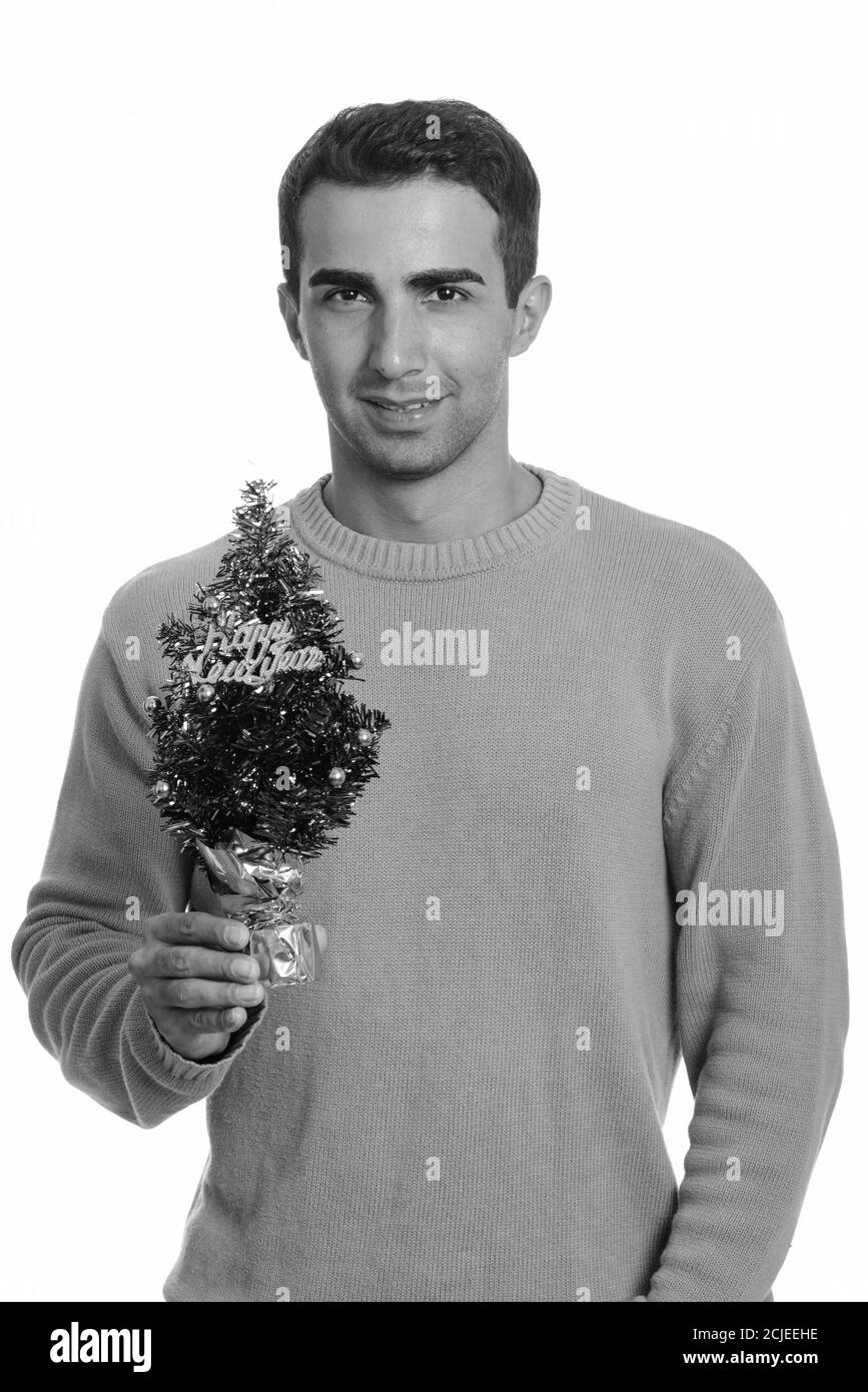 Young happy Iranian man holding Merry Christmas tree ready for ...