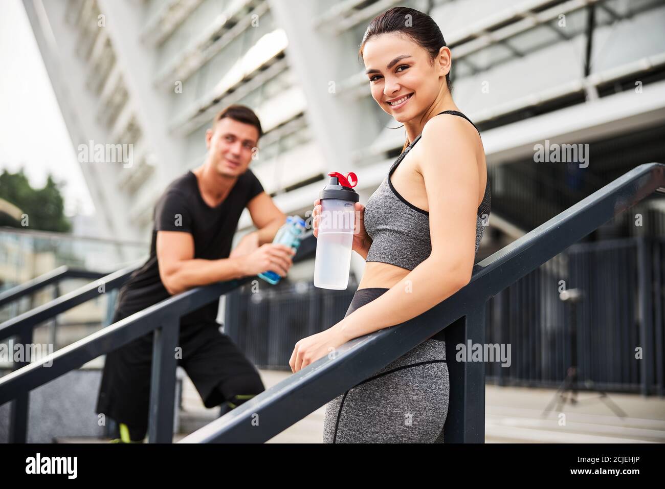 Happy young couple drinking water after workout Stock Photo - Alamy