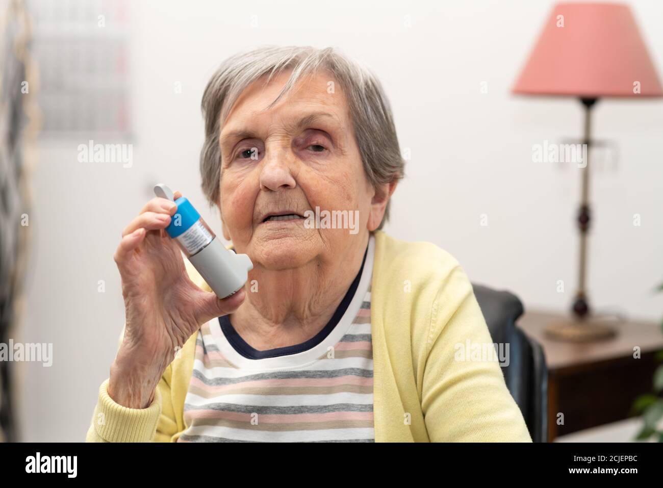 Elderly woman using an asthma inhaler Stock Photo - Alamy
