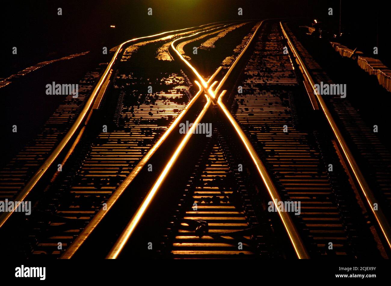 Illuminated train tracks at nightfall Stock Photo - Alamy