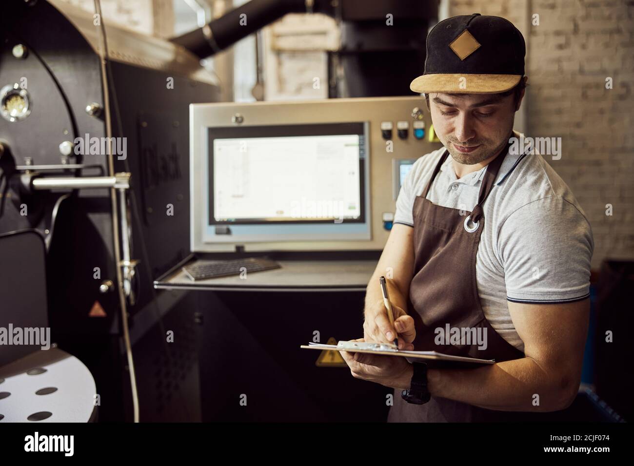 Professional roaster writing on clipboard at work Stock Photo - Alamy