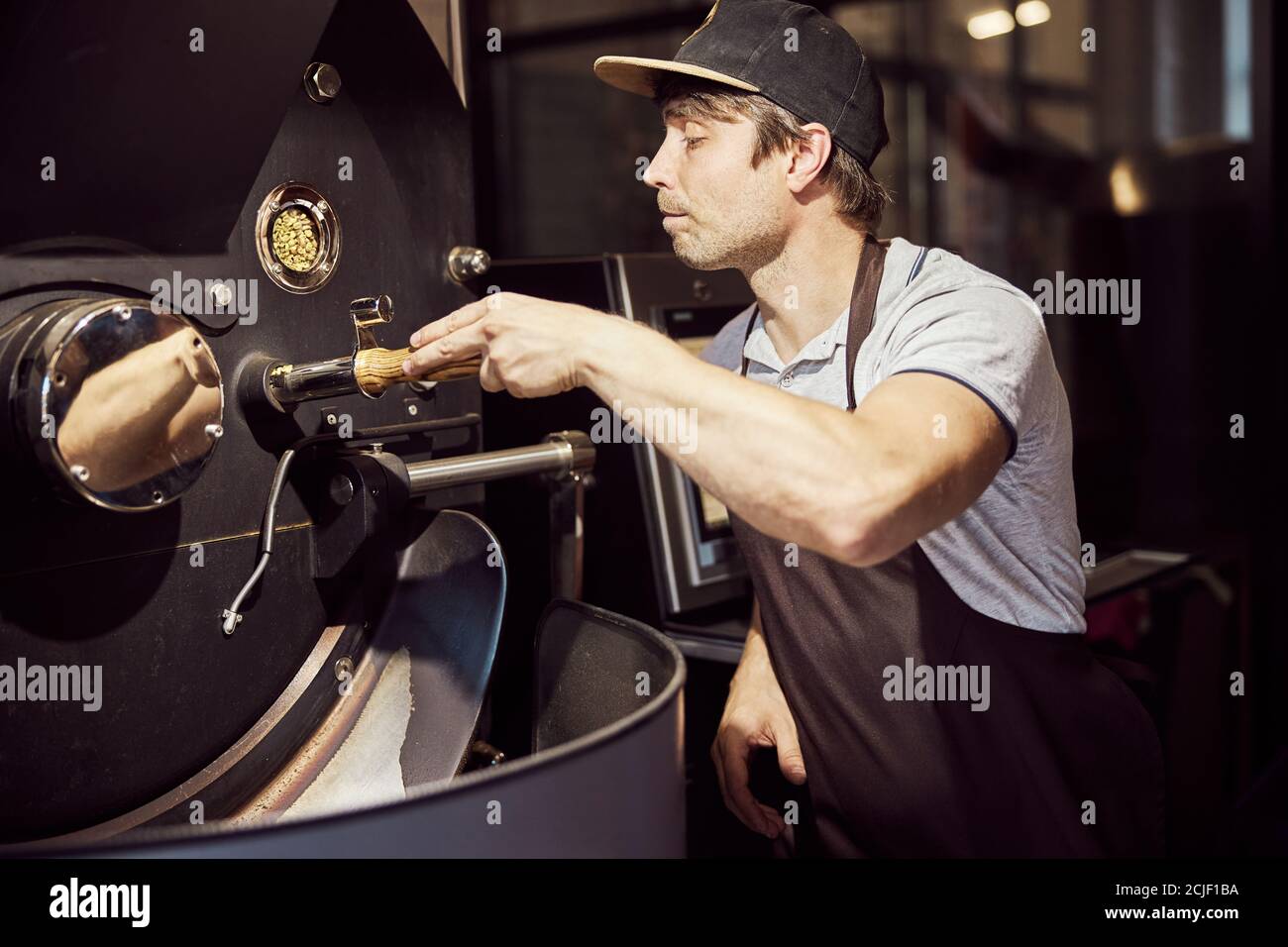 Professional roaster operating coffee roasting machine at factory Stock ...