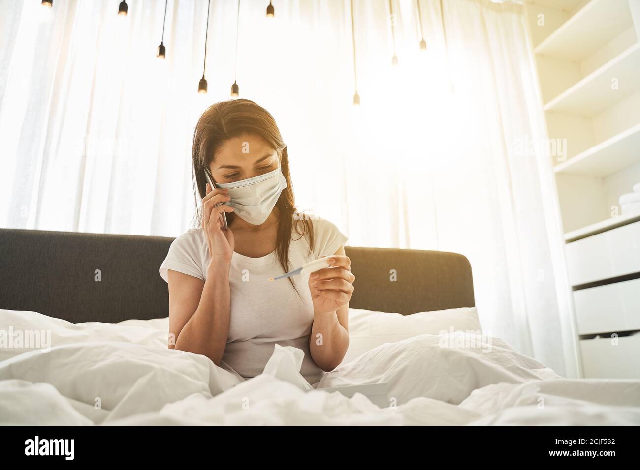 Sick female talking on the smartphone in bed Stock Photo - Alamy
