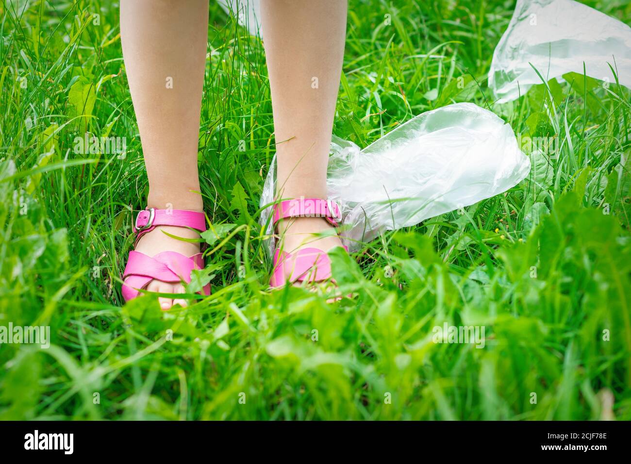plastic bags trash with children's feet on green grass while cleaning ...