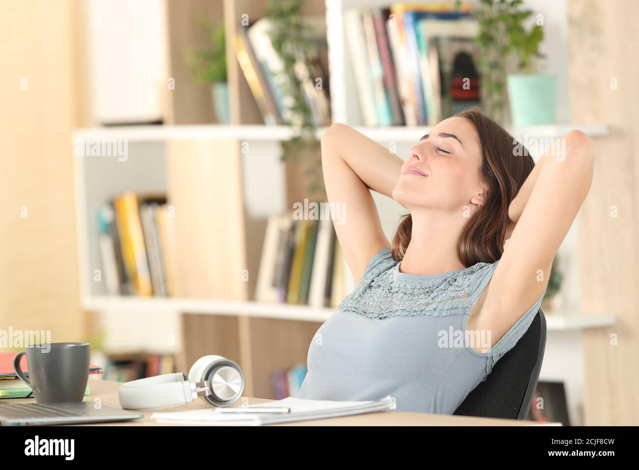 Relaxed student resting sitting on a chair in the living room at home ...