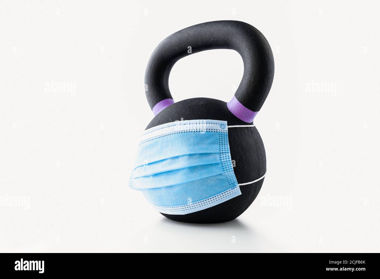 Black kettle bell with purple markings with blue surgical mask on white ...