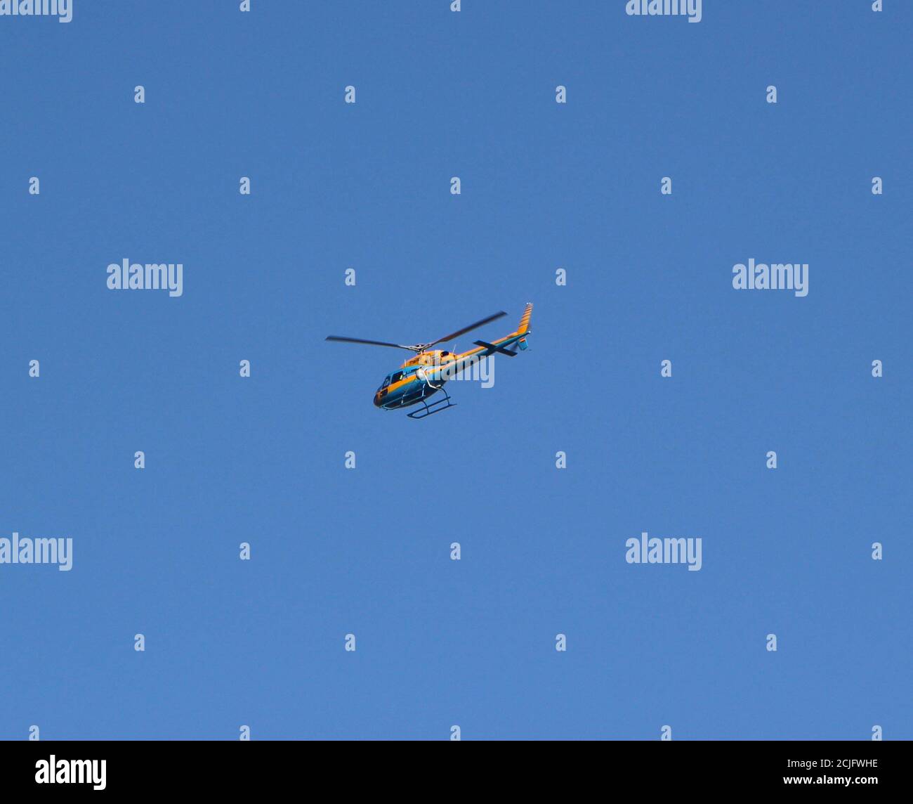 Spanish DGT traffic helicopter flying overhead against a blue sky in ...