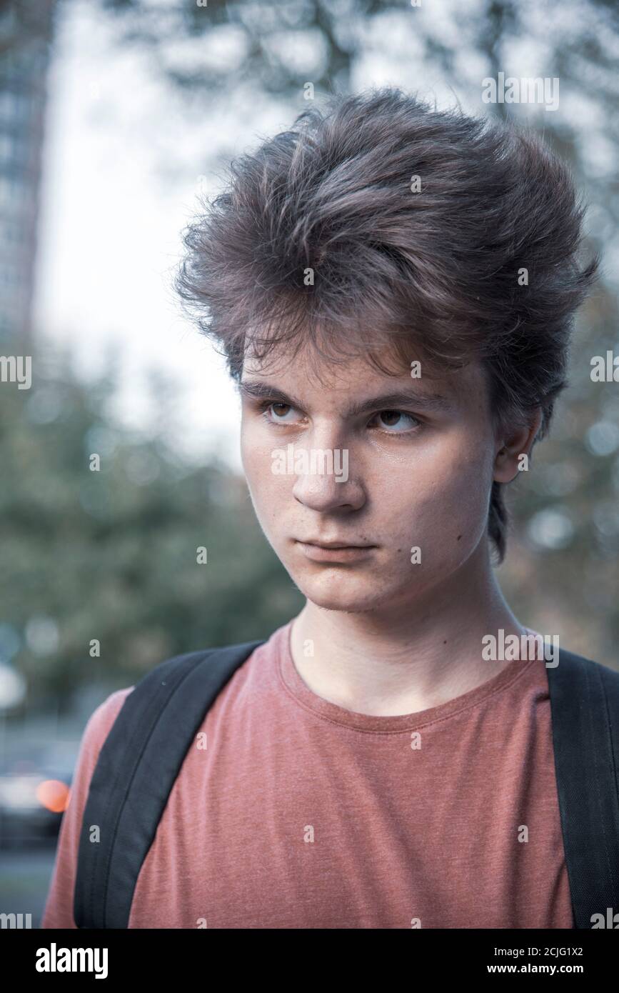 Portrait of a young teenager 17 years old in a red t-shirt with thick ...