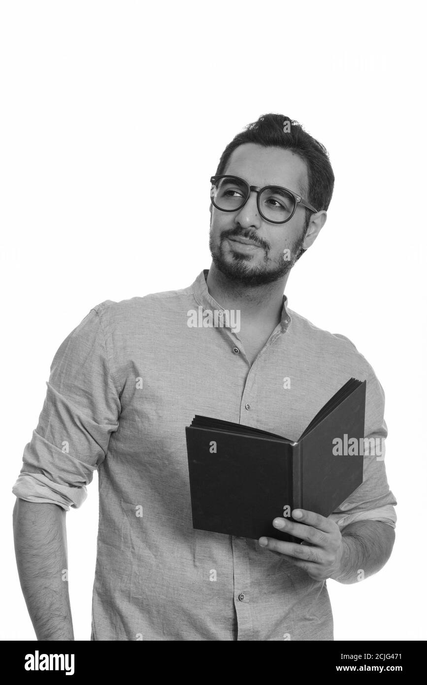 Young handsome Indian man holding book while thinking Stock Photo - Alamy