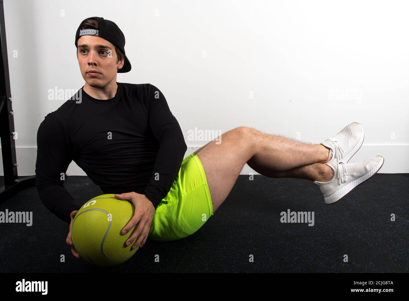 Young fit male exercising and doing the Russian twist with a ball at ...